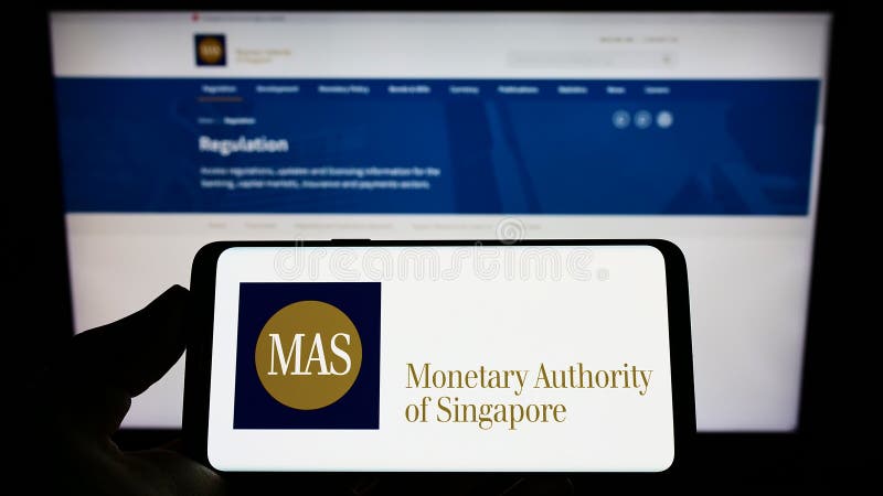 Person Holding Mobile Phone with Logo of Monetary Authority of ...