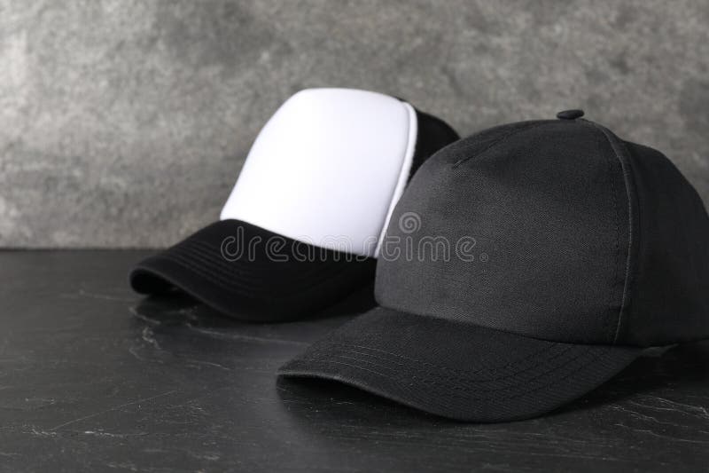 Stylish Baseball Caps on Dark Textured Table, Closeup. Mockup for ...
