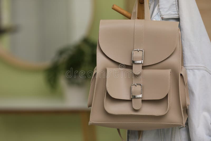 Stylish Beige Backpack and Jacket Hanging on Clothes Rack Indoors ...