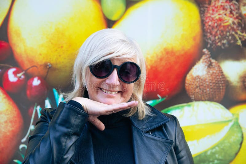 Stylish Elderly Woman Posing in Front of Vibrant Fruit Background Stock ...