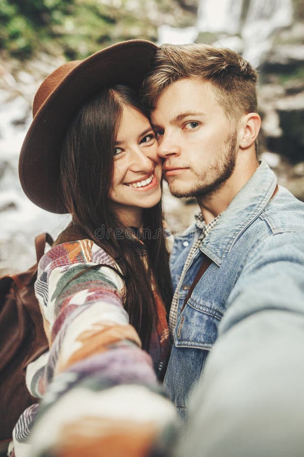 Stylish Hipster Couple Taking Selfie And Smiling At Waterfall In Stock
