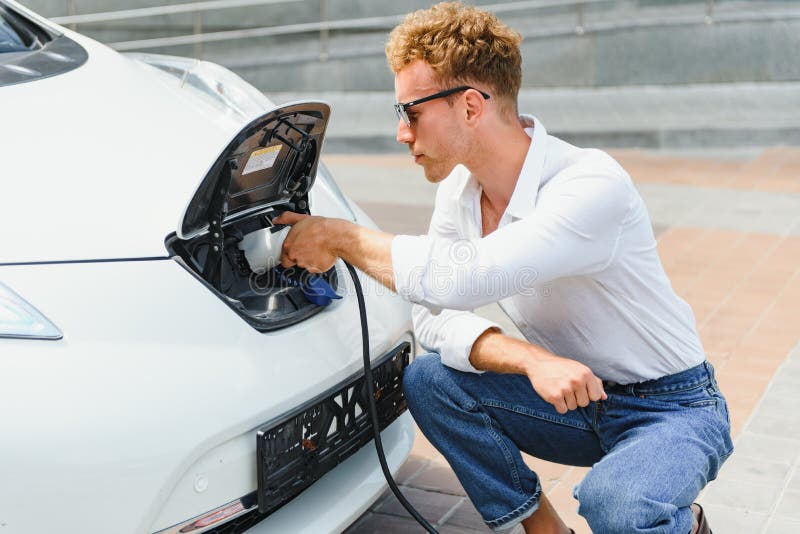 Stylish Man Inserts Plug of the Charger into the Socket of Electric Car ...