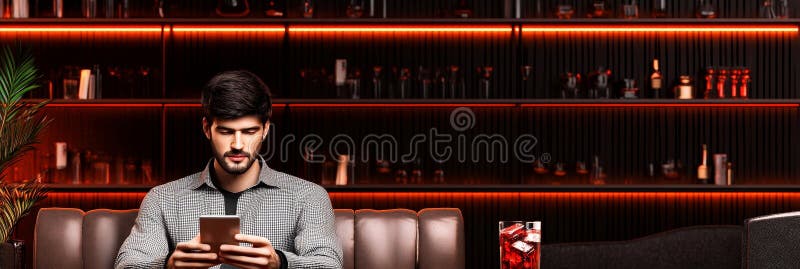 Stylish Man Using Tablet in Dimly Lit Lounge a Stylish Man Sits on a ...