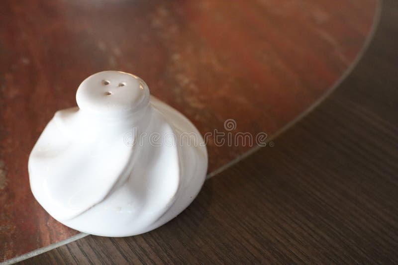 This is a Stylish White Ceramic Salt Shaker that is Placed Elegantly on ...