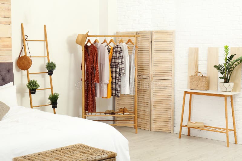 Stylish Wooden Table and Rack with Clothes in Modern Bedroom Stock ...