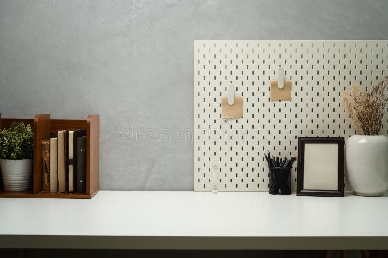 Stylish Workplace with Books, Picture Frame, Pencil Holder and Pegboard ...