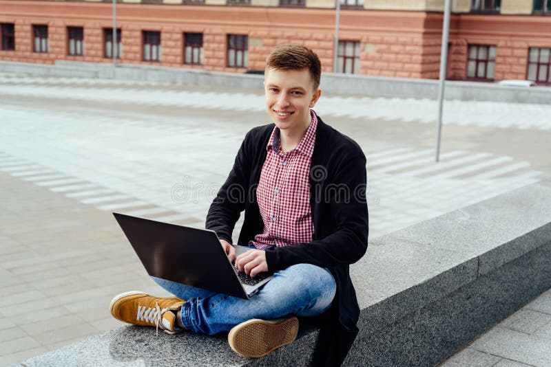 Stylish Young Man in Jacket and Jeans Sitting and Typing on Laptop ...