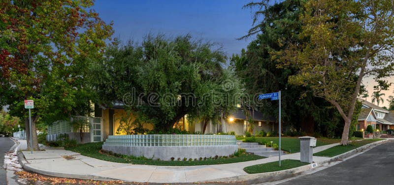 Suburban Street Corner with Lush Trees and Modern Homes at Dusk Stock ...