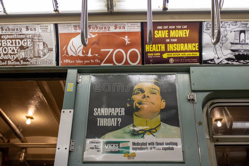 A Subway Car with Some Advertising Posters Above it and Lights Above ...