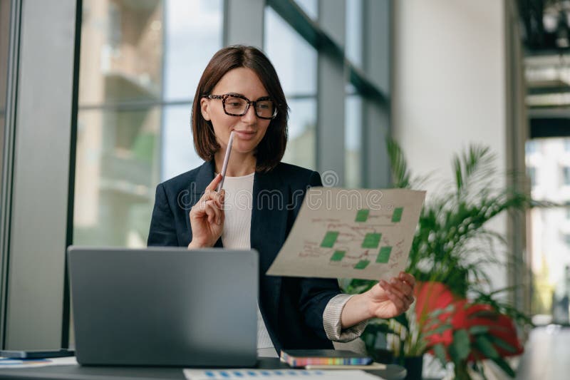 A Successful Businesswoman is Focused on Analyzing Data Reports in a ...