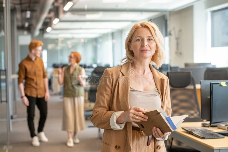 Successful Mature Blond Businesswoman with Open Notebook Looking ...