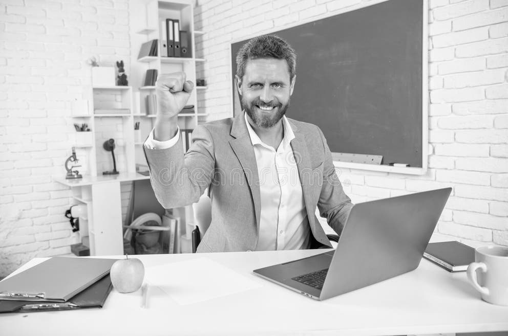 Successful School Teacher in Classroom with Computer at Blackboard ...