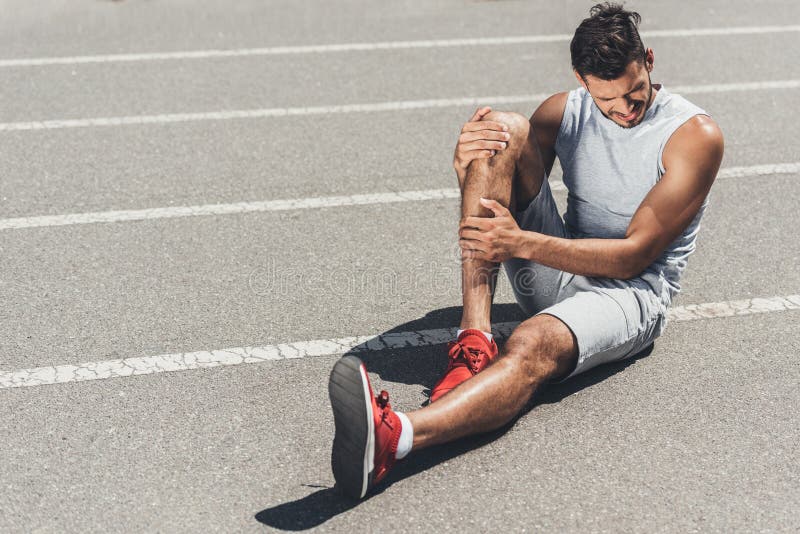 Suffering Young Runner with Leg Injury Sitting on Floor of Stock Photo ...