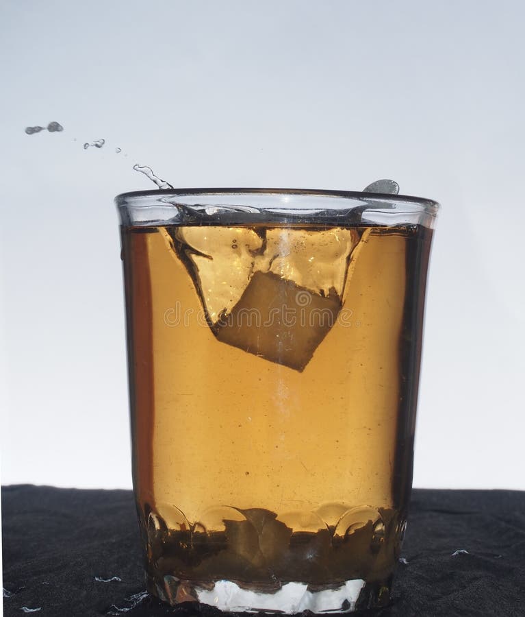 Sugar Cube Falling in a Transparent Glass Goblet with Tea. Stock Image ...