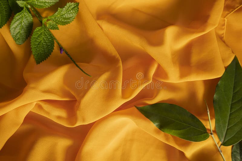Summer Concept. Yellow Scarf Fabric Texture Background and Green Leaves ...