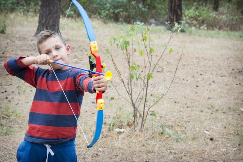 In the Summer in the Forest the Boy Shoots an Arrow. Stock Photo ...