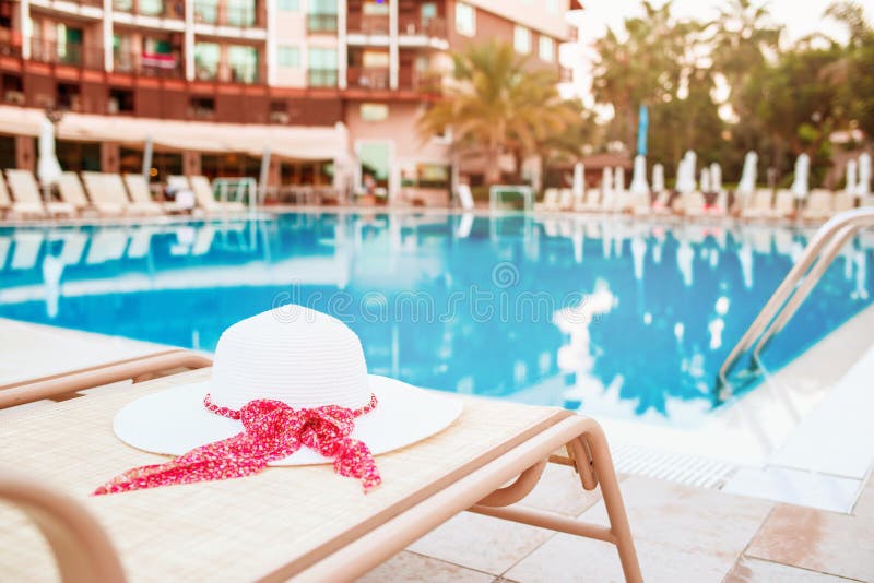 Summer Hat Lying on Deck Chair in Front of Swimming Pool. Stock Image ...