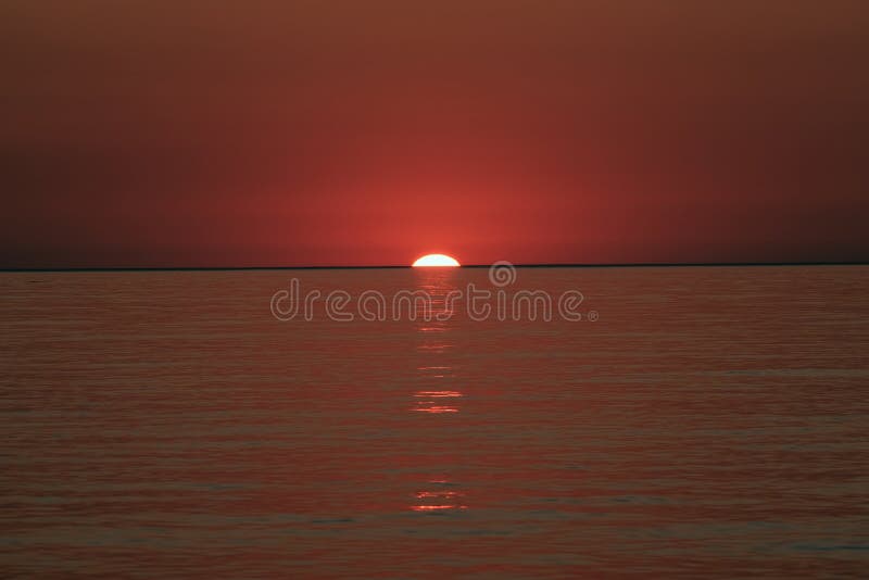 Sun Behind Sea with Waves and Red Sky at Sunset Stock Photo - Image of ...