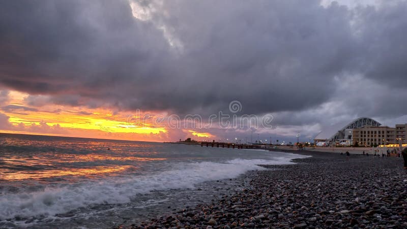 The Sun Breaks through the Black Clouds at Sunset at Sea Stock Photo ...