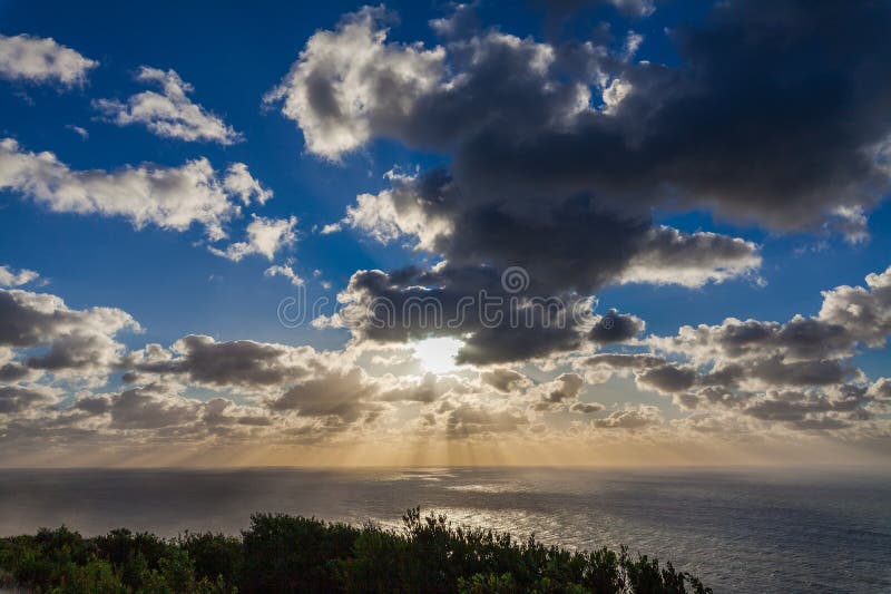 The Sun Breaks through Dramatic Clouds Over a Calm Ocean, Stock Image ...