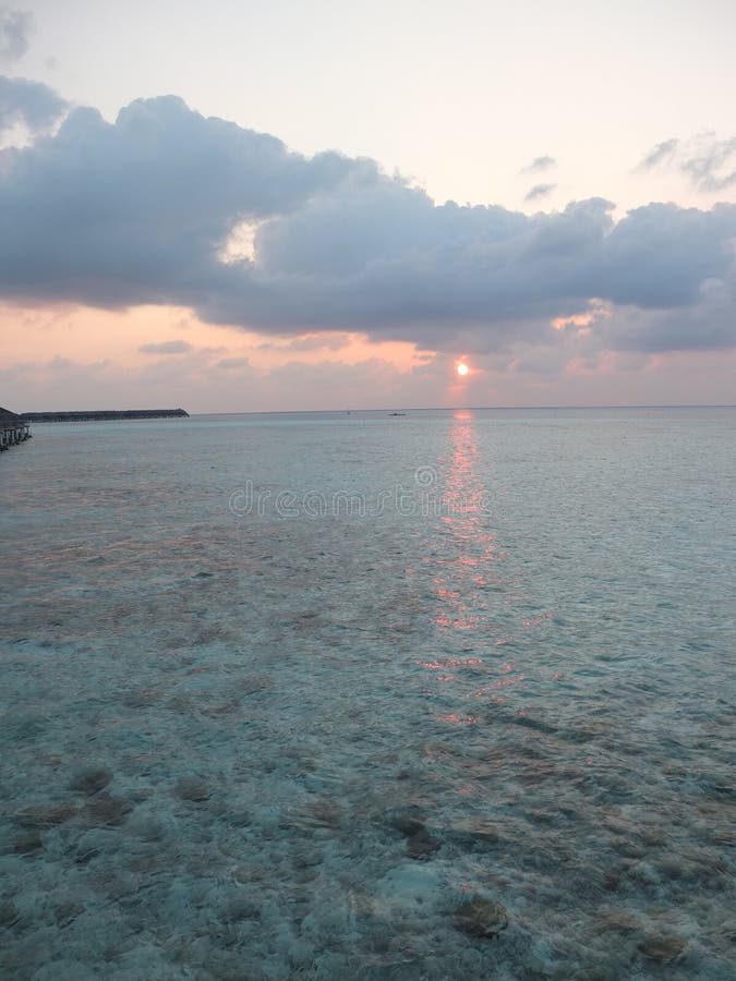 Sun Dipping with Coral Reef in Foreground Stock Image - Image of dawn ...
