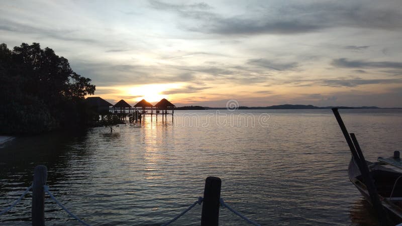 Sun down behind the huts stock photo. Image of reflection - 263060590