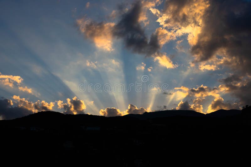 Sun Light Rays Shining through Dark Clouds Over Mountains Stock Photo ...