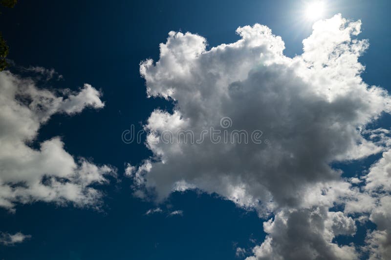 Sun Peaking Behind Dramatic White Cloud Against Blue Summer Sky at Noon ...