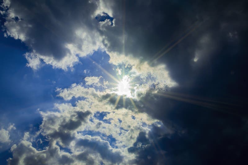The Sun Rays Break through a Thundercloud on a Blue Sky. Stock Photo ...