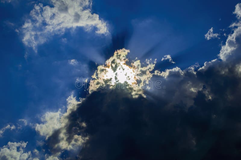 The Sun Rays Break through a Thundercloud on a Blue Sky. Stock Image ...