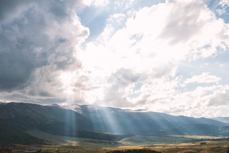 Sun Rays Breaking through Clouds, Illuminating a Valley and Mountains ...