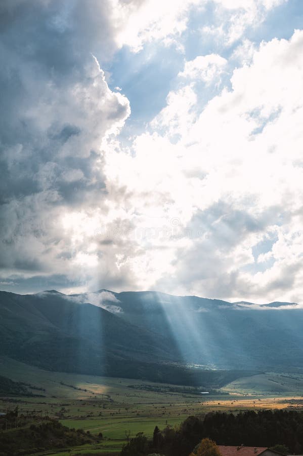 Sun Rays Breaking through Clouds, Illuminating a Valley and Mountains ...