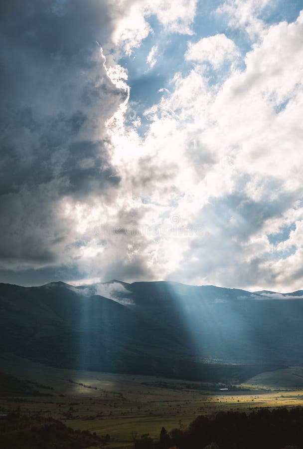 Sun Rays Breaking through Clouds, Illuminating a Valley and Mountains ...