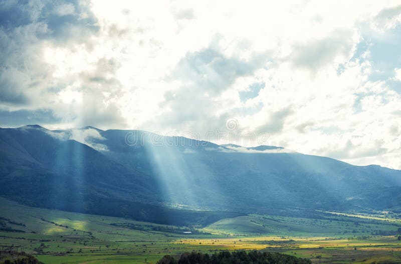 Sun Rays Breaking through Clouds, Illuminating a Valley and Mountains ...