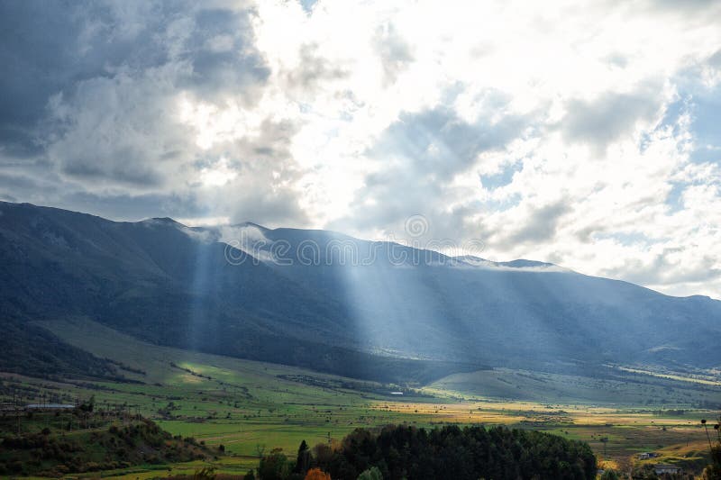 Sun Rays Breaking through Clouds, Illuminating a Valley and Mountains ...