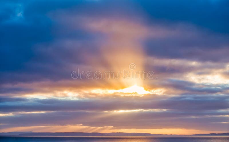 Sun Rays Bursting through Dark Blue Clouds Onto the Sea Stock Photo ...