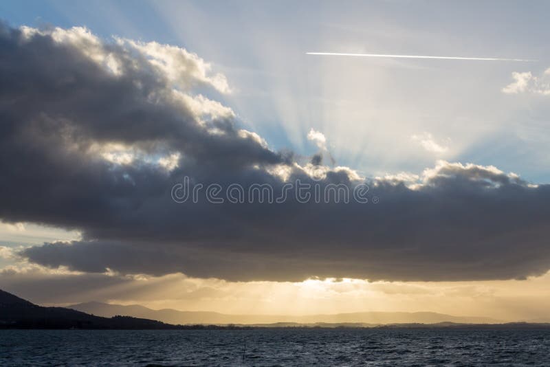 Sun Rays Coming Out through Clouds Above a Lake Stock Image - Image of ...