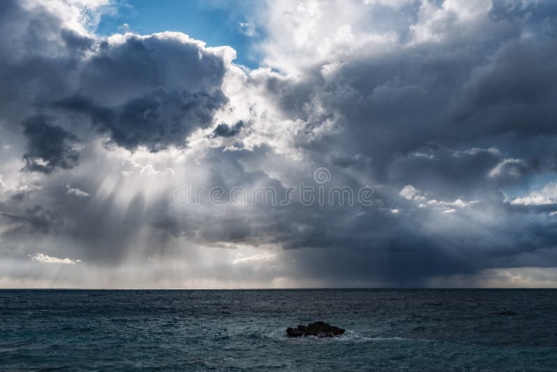 Sun Rays through Dark Rain Clouds Over the Sea Stock Photo - Image of ...