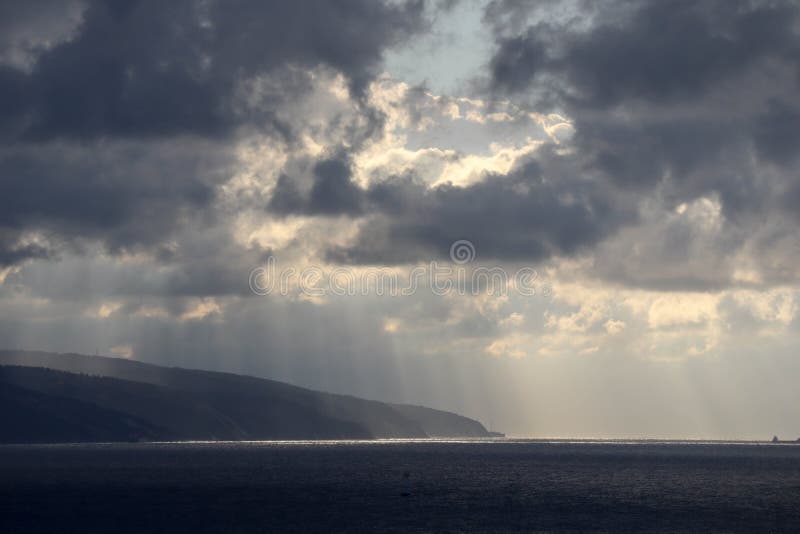 The Sun Rays Shine through the Clouds on the Sea Surface Stock Photo ...
