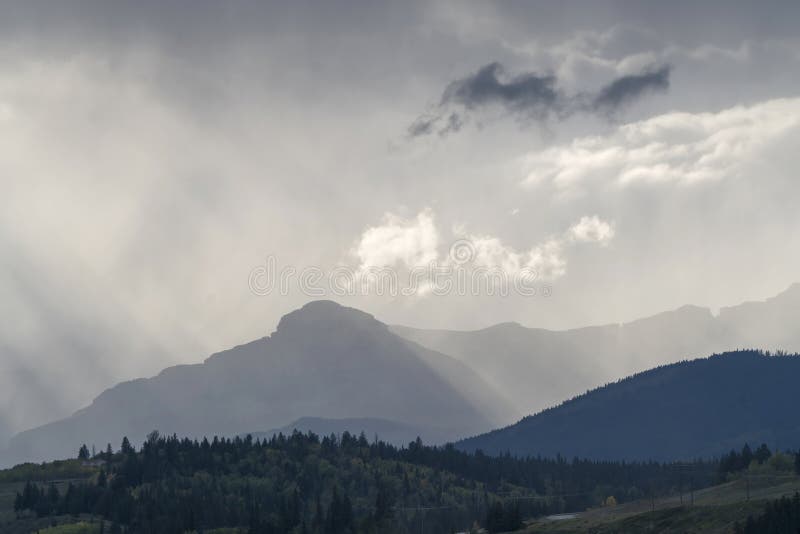 Sun Rays Shining through Rain Clouds Over Mountain Range Stock Photo ...