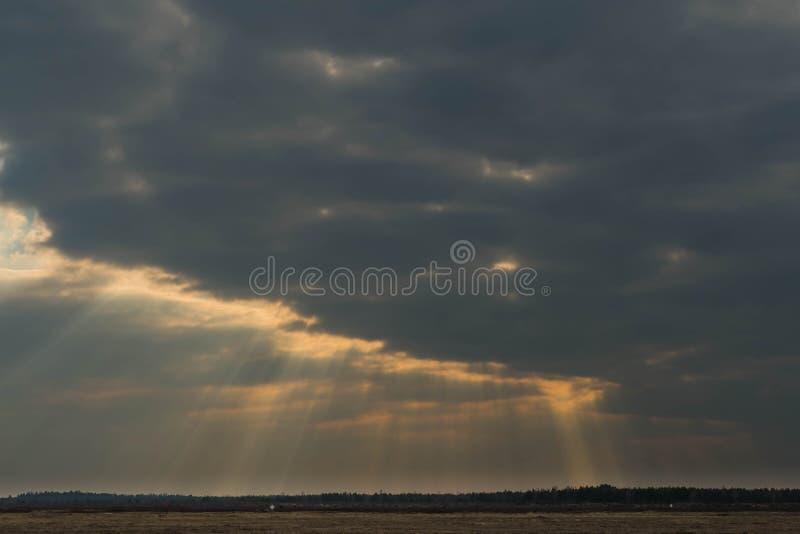 Sun Rays Streaming Down the Streaks of Dark Clouds. Stock Photo - Image ...
