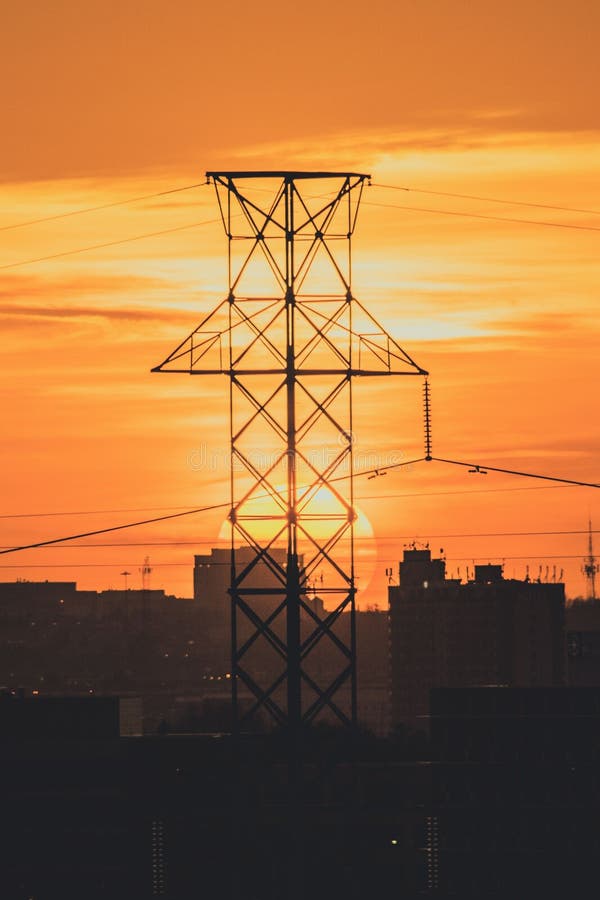 The Sun Sets Behind an Orange Sky and Silhouetted Electrical Tower ...