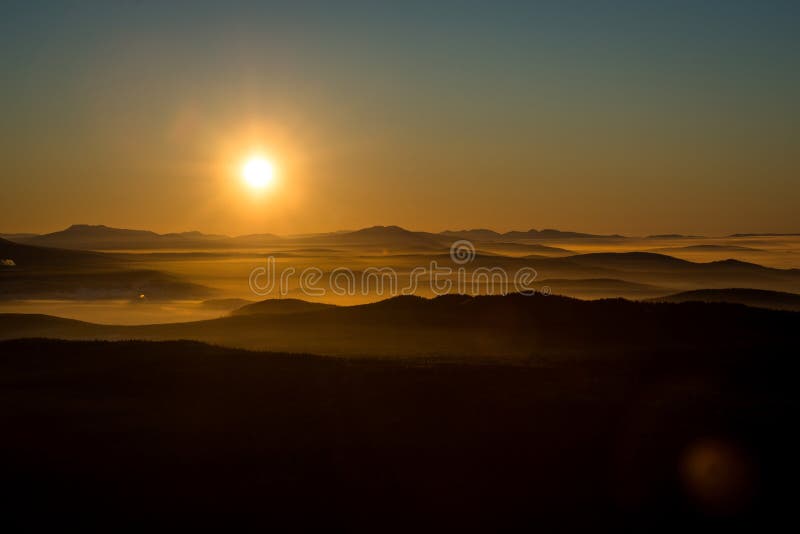 The Sun Sets Below the Horizon and Illuminates the Fog in the Valley ...