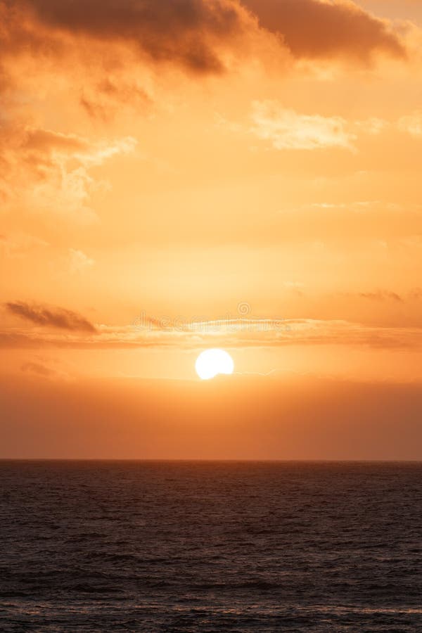 Vertical Sunset Over the Ocean Creates a Vibrant Orange Sky and Calm ...