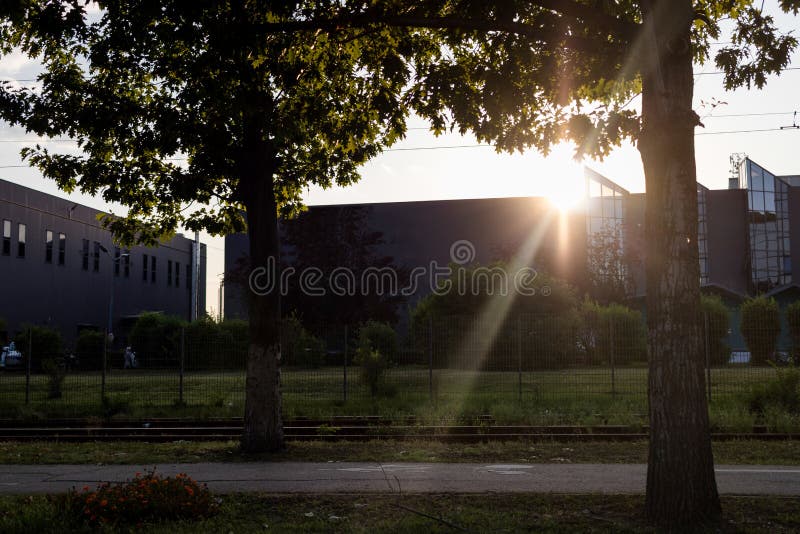 Sun Setting Behind Office Building with Trees in Front Stock Image ...