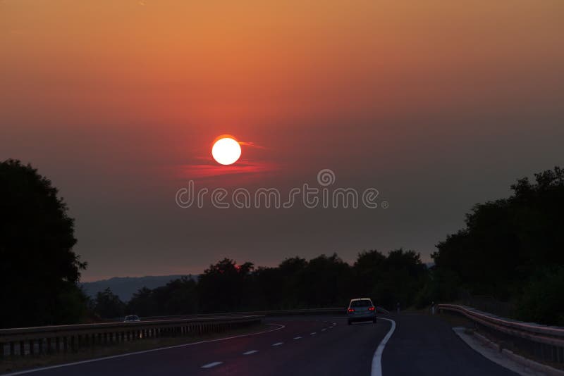 The Sun is Setting in the Distance Over a Highway and Trees Stock Photo ...