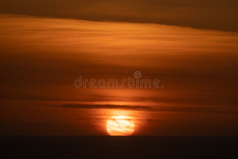 The Sun Setting on the Horizon Over the Ocean with the Whole Sky Orange ...