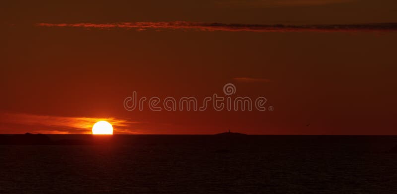 The Sun Setting in the Ocean with Small Islands and a Lighthouse in the ...