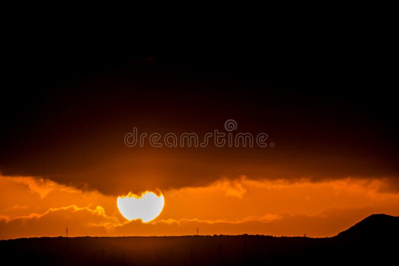 The Sun is Setting Over a Hill, Casting a Warm Orange Glow Over the ...