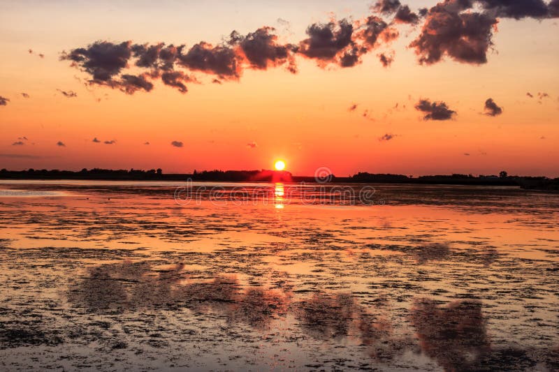 The Sun is Setting Over a Large Body of Water, Creating a Beautiful ...